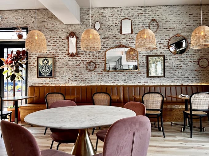 Vintage mirrors adorn exposed brick while pink velvet chairs invite you to linger—breakfast with a side of interior design inspiration.
