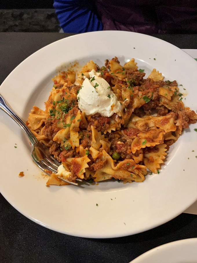 Farfalle Bolognese wearing a dollop of ricotta like a jaunty hat—pasta butterflies swimming in a rich meat sauce that tastes like somebody's nonna cares about you.
