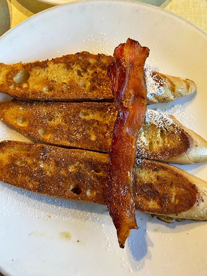 French toast that makes you question why you ever settled for lesser versions. That strip of bacon standing at attention is clearly on guard duty for this treasure.