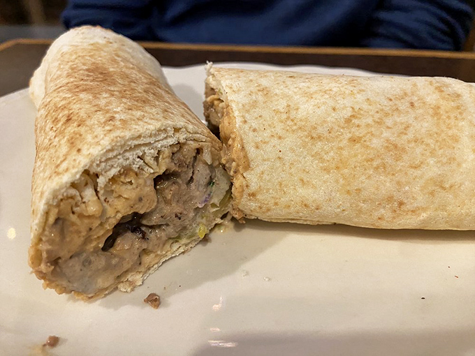 Wrapped perfection that fits in one hand. This shawarma wrap reveals its treasure of seasoned meat and veggies—portable Mediterranean bliss.