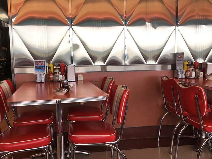 Retro details that Instagram filters try to replicate. Chrome-edged tables, red vinyl chairs, and starburst wall panels create authentic mid-century charm.