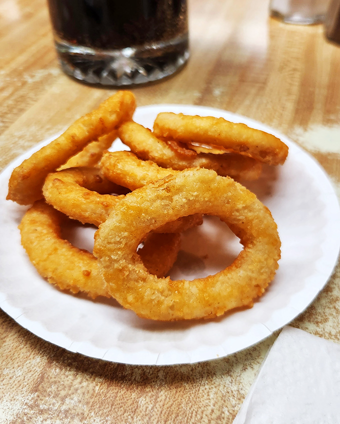 Golden-fried onion rings that crunch like autumn leaves, serving as the perfect supporting act to the headlining burger and root beer.