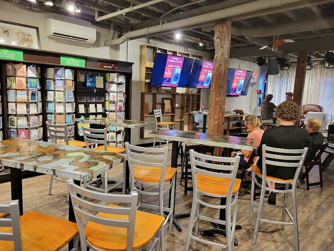 The café seating area transforms into an impromptu literary salon where strangers bond over dog-eared pages and fresh perspectives.