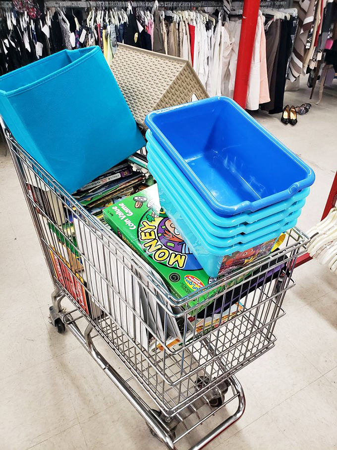 The thrifter's chariot: a shopping cart loaded with blue bins and board games, ready for a serious treasure-hunting expedition.
