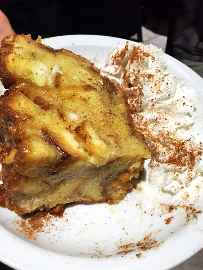 Bread pudding that makes you close your eyes with each bite—cinnamon-spiced comfort topped with a cloud of whipped cream.