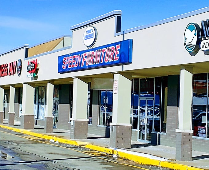 Strip mall architecture rarely inspires poetry, but this blue sign has saved more relationships than couples therapy when the old couch finally gives out.