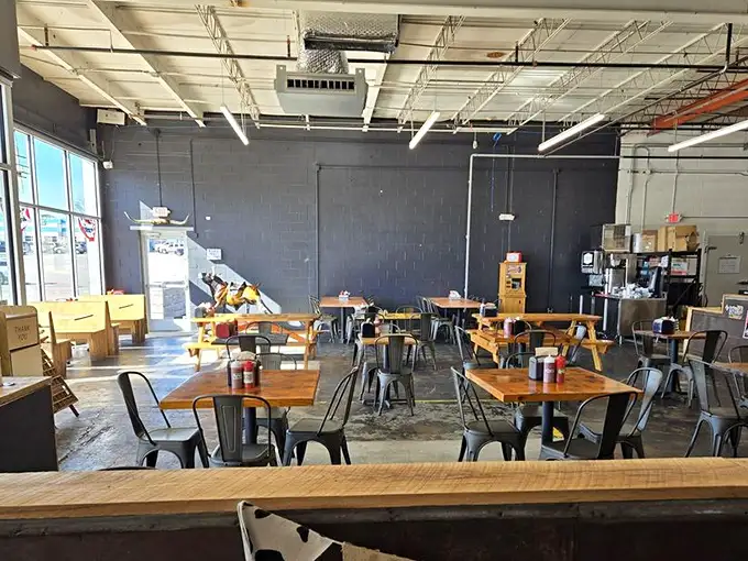 Industrial-chic meets barbecue simplicity with wooden tables, metal chairs, and an atmosphere that keeps the focus where it belongs—on the food.