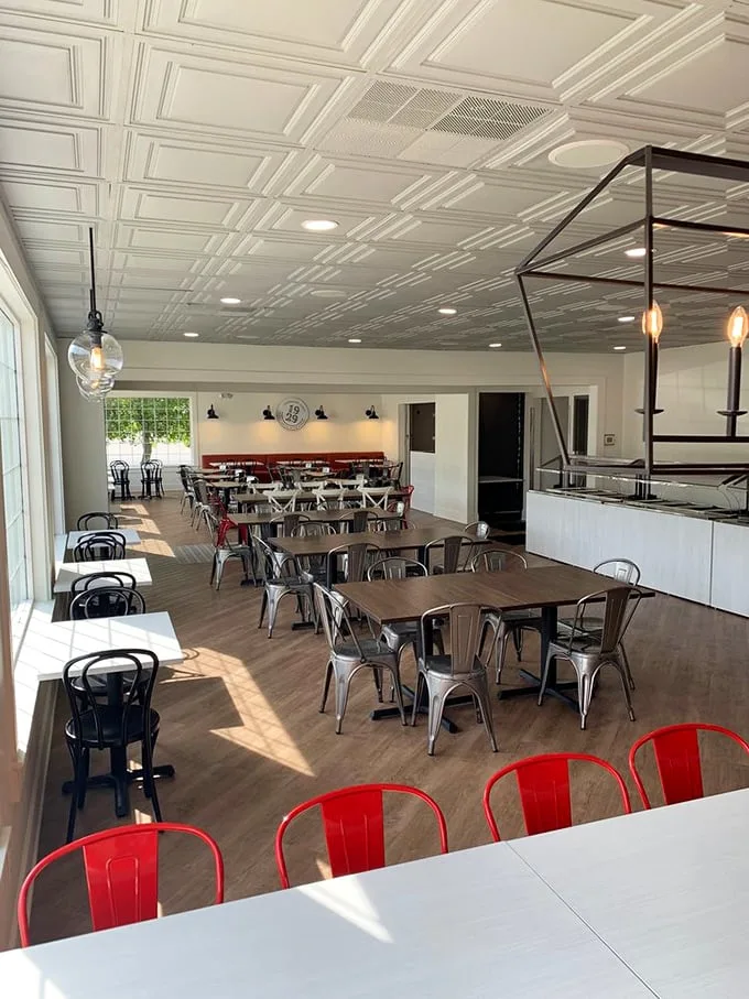 Sunlight streams across polished wood tables and those eye-catching red chairs, creating the perfect backdrop for the comfort food drama about to unfold on your plate.