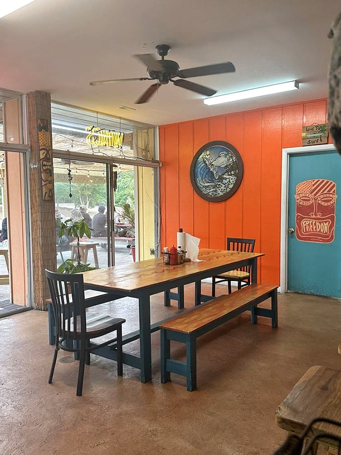 The vibrant orange and turquoise interior welcomes you with coastal charm. That stained glass marine life window? Pure beachside magic.