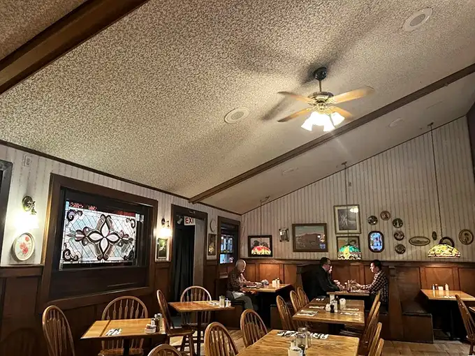 Warm wood paneling, stained glass accents, and ceiling fans spinning lazily overhead—this is what breakfast dreams are made of. The kind of place where coffee refills appear magically.