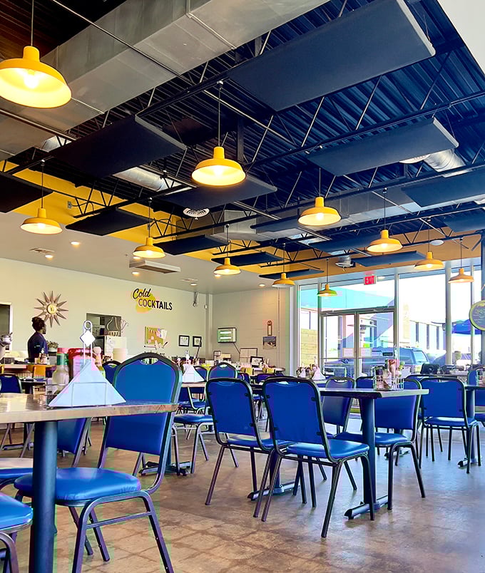 Modern industrial meets classic diner comfort with those signature blue chairs—like your favorite booth got a HGTV makeover.