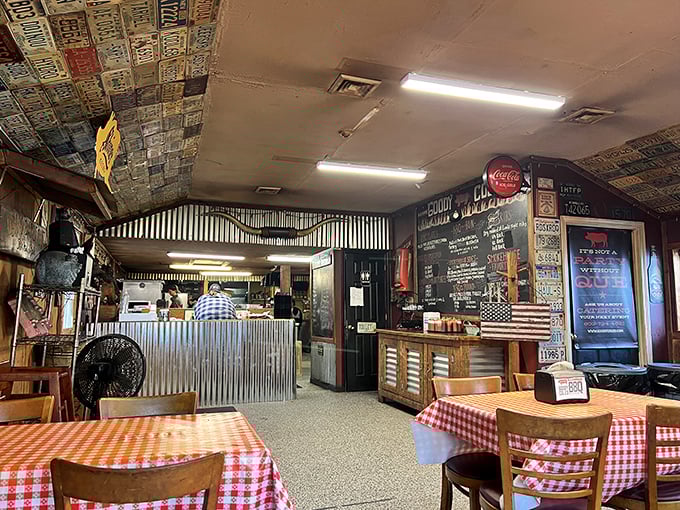 License plates from across America create a patchwork ceiling above classic red-checkered tables. It's not just decoration—it's a road map of barbecue pilgrims.
