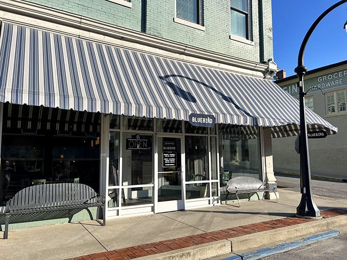 The Bluebird's striped awning isn't just charming decor—it's practically a beacon signaling "good food and conversation ahead" to weary travelers.