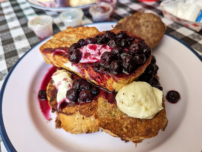 Golden-brown French toast islands floating in a blueberry sea with dollops of cream—breakfast that looks like it graduated from culinary art school.