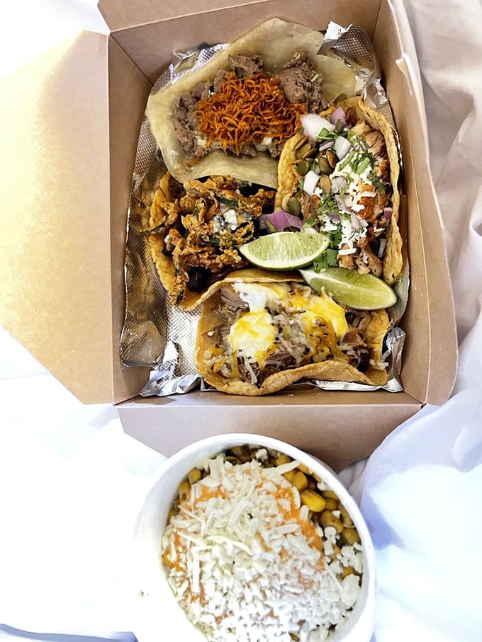 Behold the humble cardboard container, elevated to art form. These tacos aren't just arranged—they're composed, with each garnish playing its perfect role.