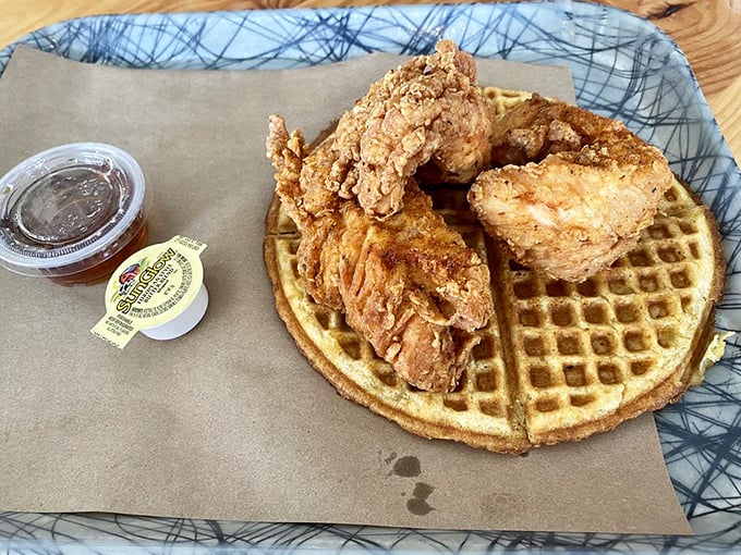 Golden-crisp chicken perched atop a waffle throne, accompanied by syrup in its formal attire—this isn't breakfast, it's edible royalty holding court.