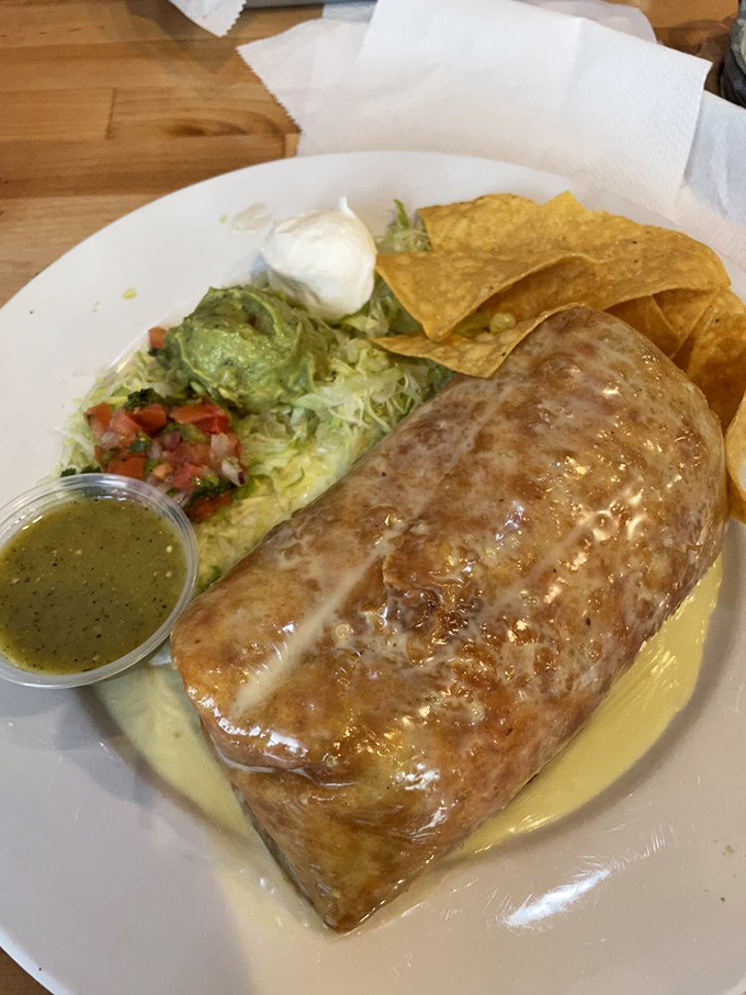 Behold the chimichanga in its natural habitat – gloriously golden, swimming in queso, and practically begging to be photographed before devoured.