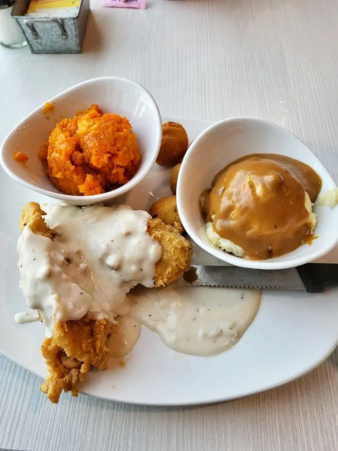 Behold the holy trinity of Southern comfort: country fried chicken smothered in gravy, cloud-like mashed potatoes, and that bright carrot soufflé that's worth the drive alone.