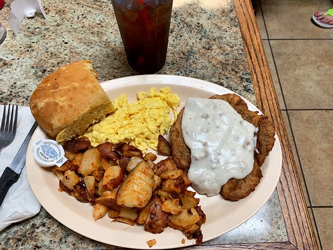 Behold the holy trinity of breakfast perfection: golden hash browns, fluffy scrambled eggs, and the star of the show—country fried steak smothered in peppery gravy.