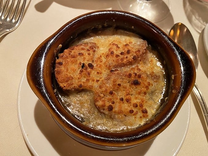 The French onion soup arrives with a crown of perfectly browned cheese that stretches with each spoonful. This isn't just soup—it's a warm, savory hug in a bowl.