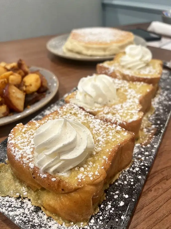 Golden slices of French toast dusted with powdered sugar and topped with perfect dollops of cream – proof that simplicity can be stunning.