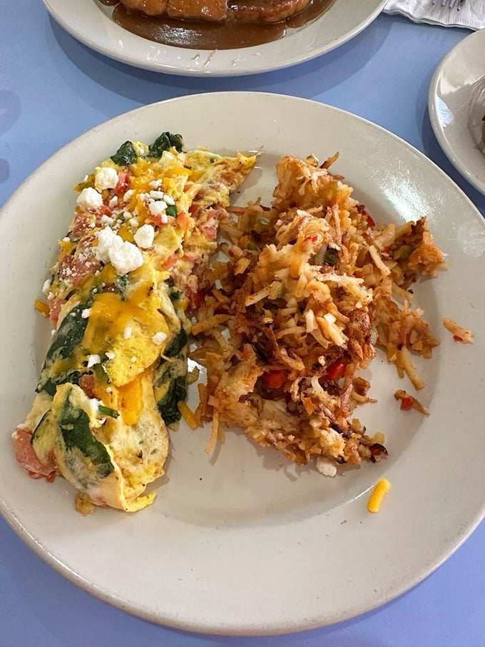 Behold the Greek omelet in its natural habitat – a plate barely containing its cheese-laden glory. Those hash browns deserve their own fan club.