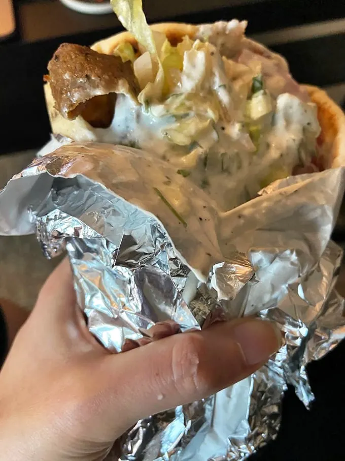 This isn't just a gyro – it's a handheld masterpiece. Creamy tzatziki cascades over perfectly seasoned meat, all wrapped in foil like the culinary gift it is.