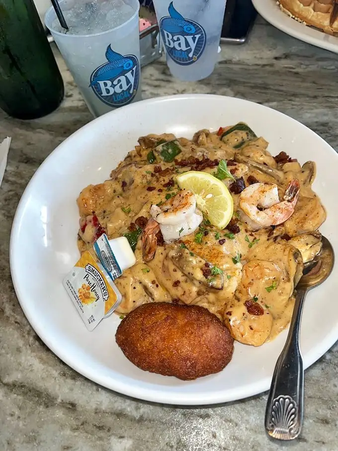 Behold the superstar! Creamy grits, perfectly seared shrimp, bacon bits, and that sauce – this dish isn't just served, it's unleashed upon your taste buds.
