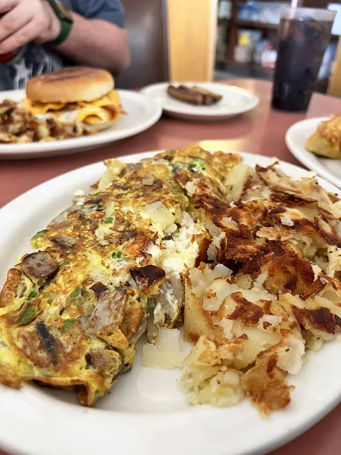 Breakfast alchemy at its finest—a veggie-packed omelet nestled against hash browns with that perfect crisp-to-tender ratio.