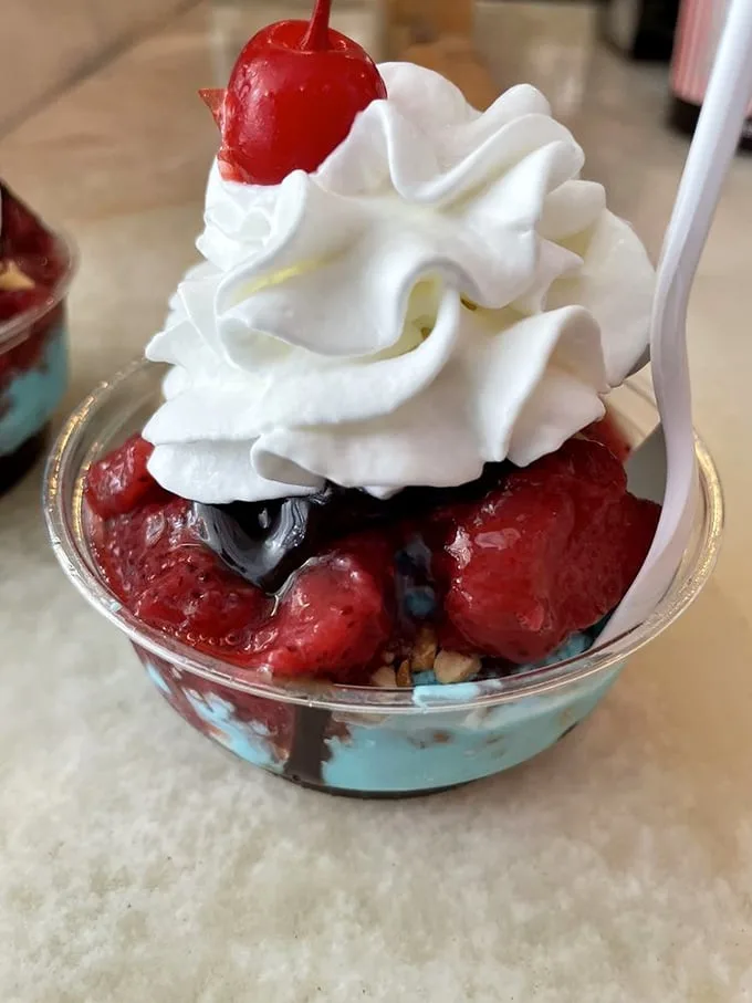 A berry sundae that doesn't just satisfy a craving—it creates new ones. That whipped cream mountain with its cherry flag claims victory over ordinary desserts.