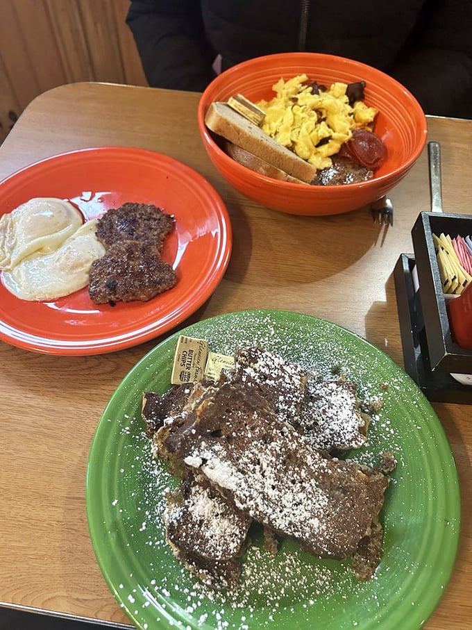 A breakfast trinity: eggs, sausage, and French toast dusted with powdered sugar—proof that good things really do come in threes.