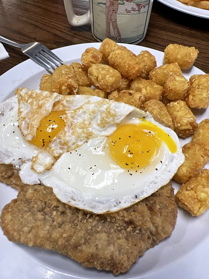 The holy trinity of diner breakfast: perfectly runny eggs, crispy tots, and chicken fried steak. The kind of plate that makes you want to high-five the cook.