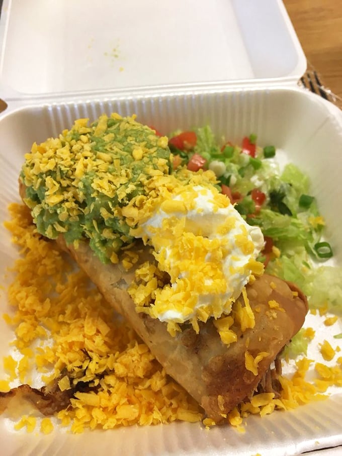 The chimichanga in its natural habitat—crispy exterior giving way to savory filling, topped with the holy trinity of sour cream, guacamole, and shredded cheese.