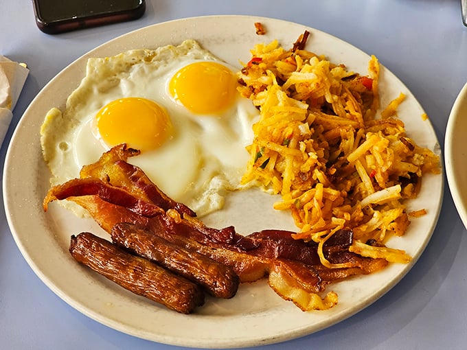 The holy trinity of breakfast perfection: sunny-side up eggs, crispy bacon, and home fries that could make a potato proud.