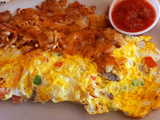 This omelet doesn't just come with hash browns—it arrives with a golden-brown crown of potato perfection that deserves its own zip code.