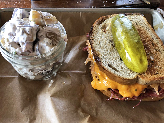 The Reuben sandwich stands proud with a pickle spear crown—a perfect marriage of corned beef, sauerkraut, and melty cheese that demands both hands and zero shame.