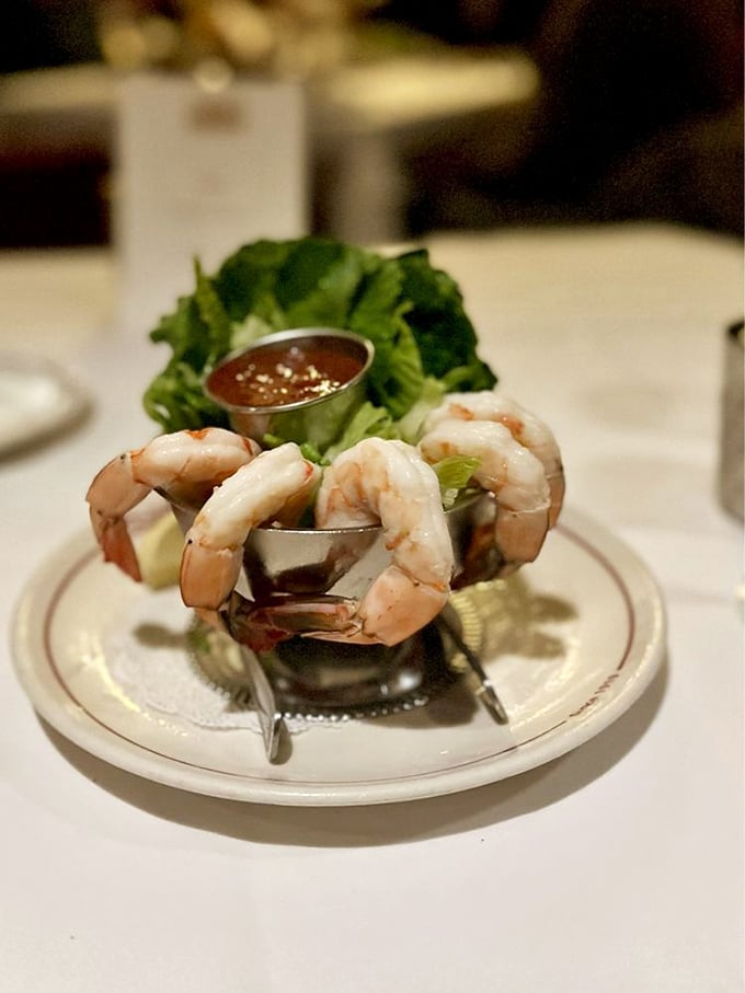 Shrimp cocktail that defies gravity—plump crustaceans hanging off the edge like daredevils, waiting for their horseradish-spiked dive.
