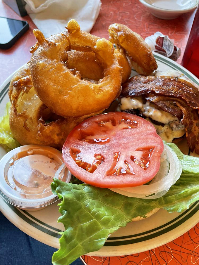 This isn't just a burger—it's architecture. Crispy onion rings, fresh tomato, and a perfectly cooked patty create a towering tribute to American ingenuity.