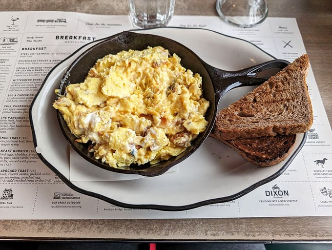 Scrambled eggs nestled in a skillet of comfort. The accompanying toast stands ready for the sacred ritual of yolk-sopping that unites breakfast lovers everywhere.