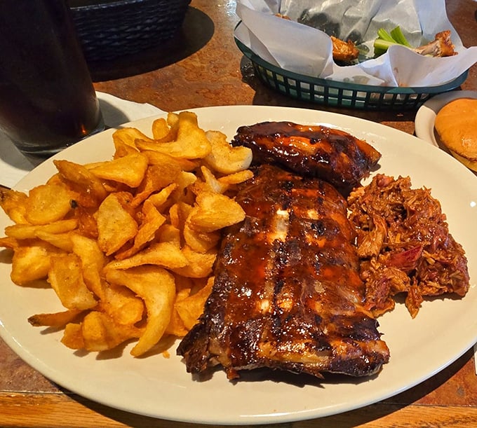 The perfect trifecta—glistening ribs, golden chips, and pulled pork that looks like it's been slow-dancing with barbecue sauce all day long.