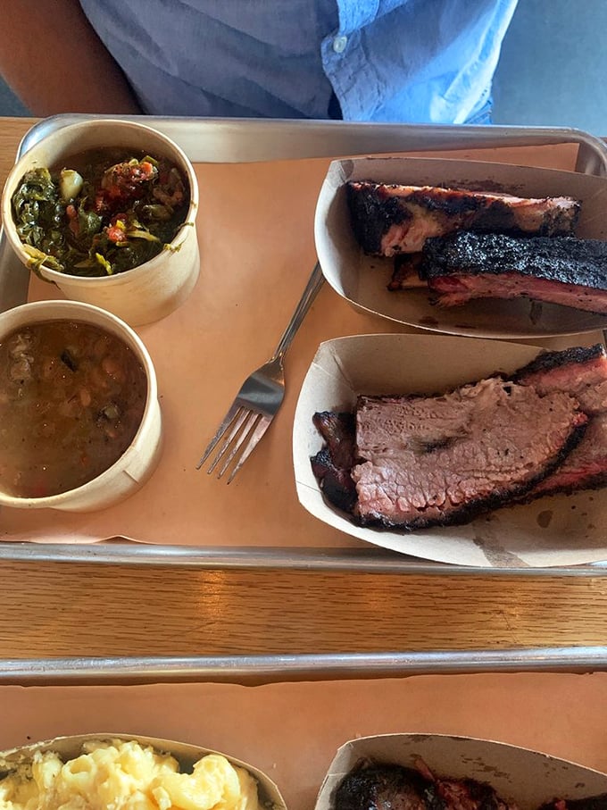 A tray of smoky treasures alongside collard greens and beans. This isn't just lunch—it's a Southern revival meeting on a plate.