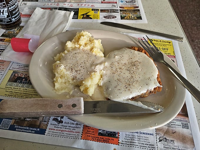 This isn't just country fried steak – it's a masterpiece of contrasts where crispy golden exterior meets tender meat, all blanketed in gravy that could solve world peace.