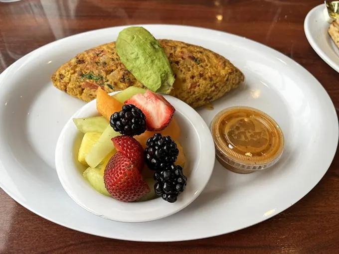The Mexican omelette arrives with a side of fresh fruit—nature's apology for how decadent the main attraction is.