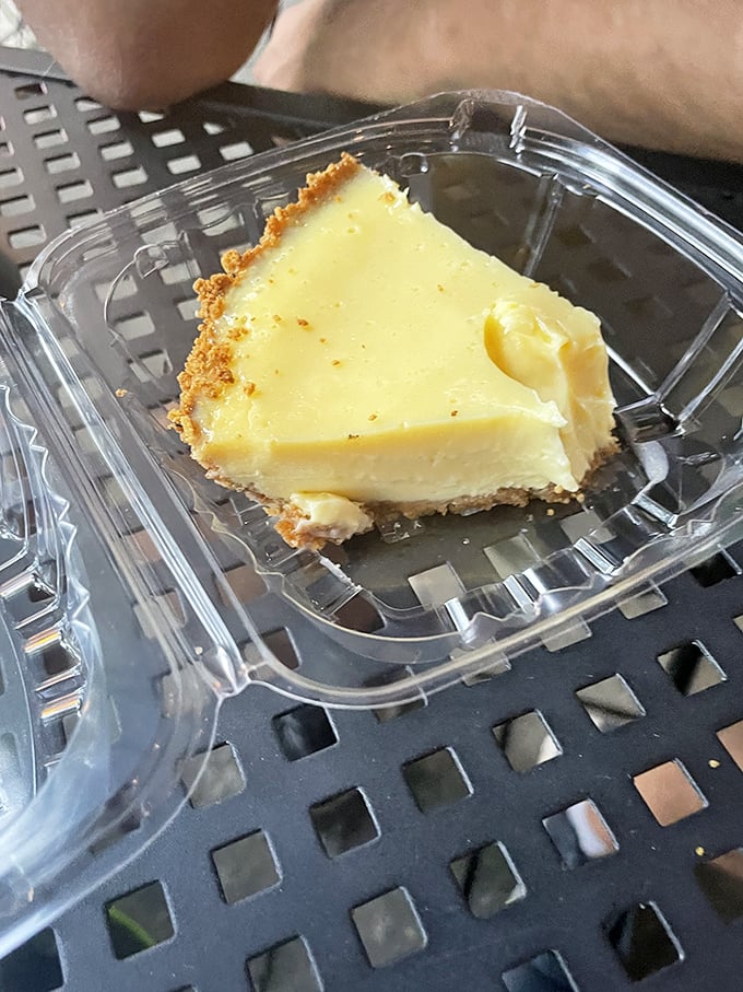 This slice of key lime heaven comes in a humble plastic container, proving great food doesn't need fancy packaging—just impeccable execution.