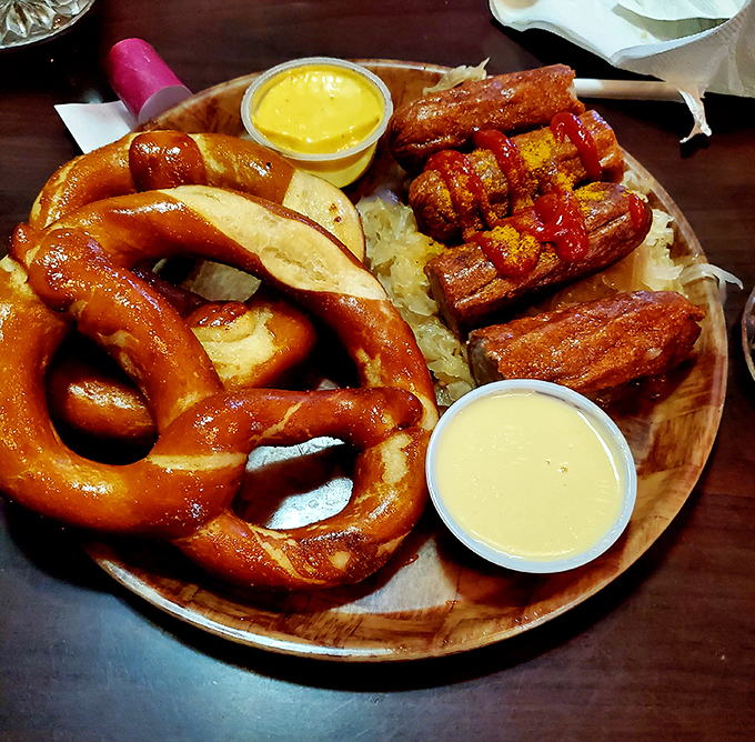 When a pretzel, bratwurst, and beer cheese share a wooden plate, they're not just food – they're a diplomatic summit of German flavors negotiating deliciousness.