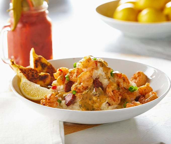 Food photographers dream of this moment: perfectly sautéed shrimp bathed in savory sauce atop creamy grits—comfort food that's dressed for the opera.