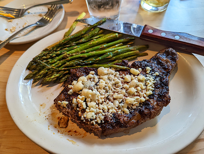 This blue cheese-crusted steak stands proudly beside asparagus spears that glisten with attention, a duo performing a perfectly choreographed flavor ballet.