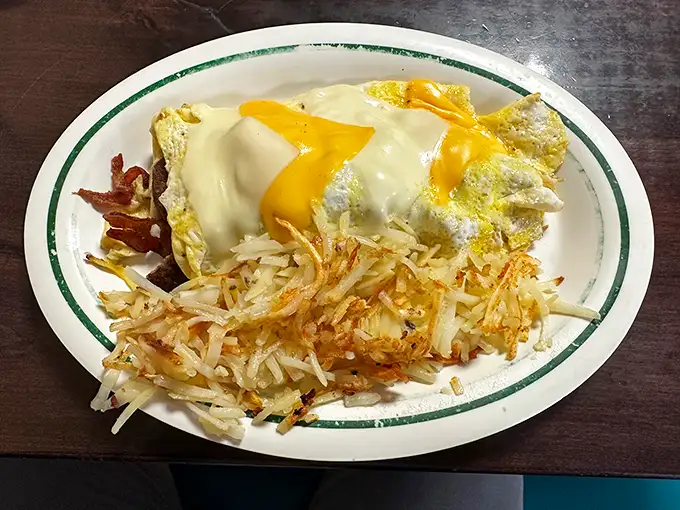 Eggs wearing a melted cheese tuxedo next to hash browns dressed for success. This plate doesn't just feed you—it respects you.