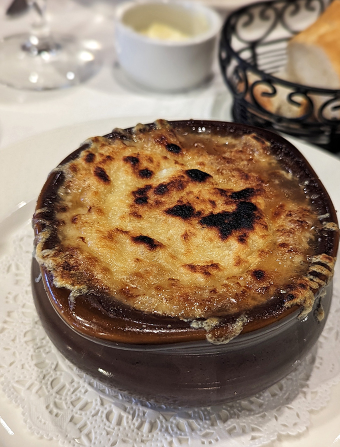 Another angle of the legendary French onion soup—where the broiled cheese forms a magnificent crust that gives way to the rich, savory broth beneath.