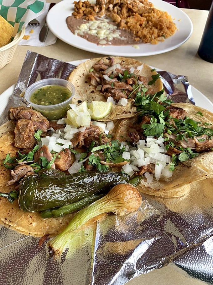 Carnitas tacos with all the fixings—the kind that make you close your eyes on the first bite. That grilled onion and jalapeño are the backup singers that steal the show.